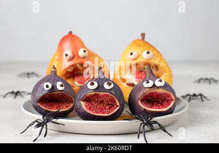 Spooky pear and fig monsters for Halloween party on wooden board ...