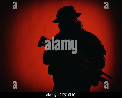 Soldier in camouflaged uniform armed with military equipment, next to ...