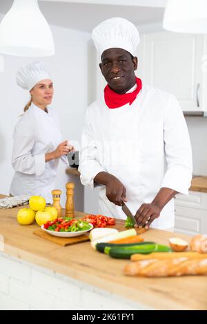 Two female and male cooks wearing uniform working on kitchen Stock ...
