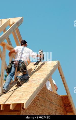 Roofers putting on sub roof of particle board on new home construction ...
