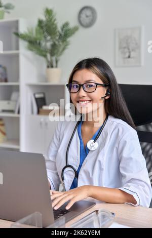 Young Asian female doctor using digital tablet talking on phone for ...