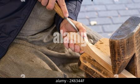 Hands carving spoon from wood, working with chisel close up. Process of ...
