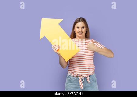 Pretty girl smiling and pointing like while sitting with her friends ...