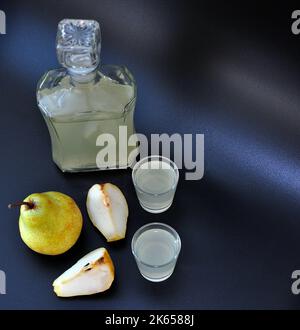 Pear calvados and pieces of ripe fruit next to a bottle and glasses on ...