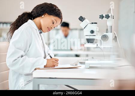 Young woman scientist writing report listening audio message at ...