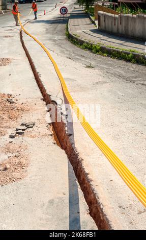 Worker inserts fiber optic cables buried in a micro trench Stock Photo ...
