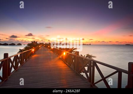 Long bridge heading to beautiful resort at Mabul Island during sunset ...