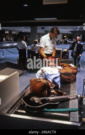 US Customs officers inspect the luggage of multiracial arriving ...