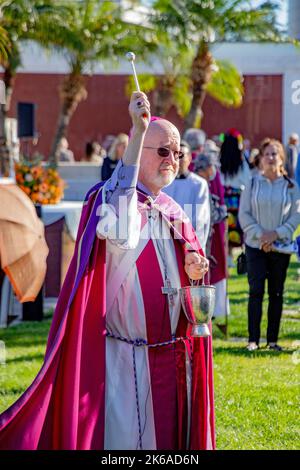 Sprinkling holy water with an aspergillum, a bishop conducts a ...