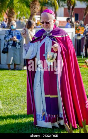 Sprinkling holy water with an aspergillum, a bishop conducts a ...