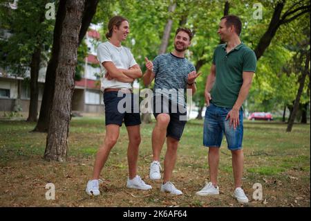 Three handsome young men having fun in a park Stock Photo - Alamy