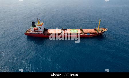 Aerial view of cargo boat with helipad moored at concrete pier on ...