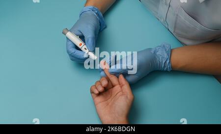 Nurse using lancelet on finger of diabetic patient to checking blood ...