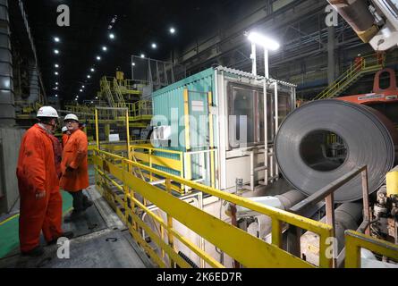 Employees at ArcelorMittal Dofasco, a manufacturer of hot rolled steel coils, look on at a ...