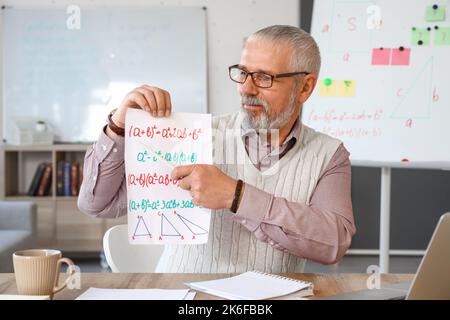 Mature teacher conducting Math lesson online at home Stock Photo - Alamy