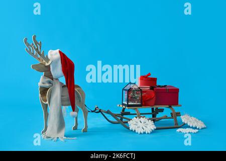 Wooden reindeer with scarf, sledge and Christmas tree on red background ...
