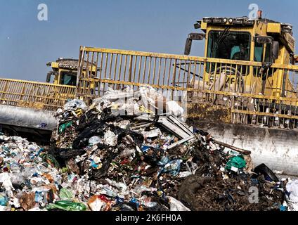Municipal waste landfill. Workers with trucks and bulldozers at work in ...
