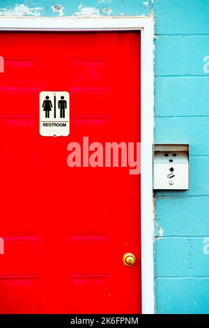 A blue restroom sign with male and female symbols is mounted on a ...