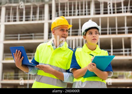 Two engineers are discussing an important project, holding a laptop and ...