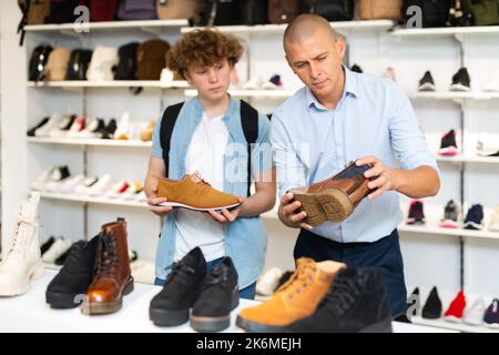 Male shop assistant consulting teenager in shoes store Stock Photo - Alamy