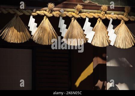 A sacred rice straw rope (shimenawa) marks the entrance to a Shinto ...