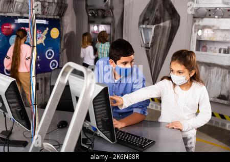 Enthusiastic children in protective masks play in the quest room of ...