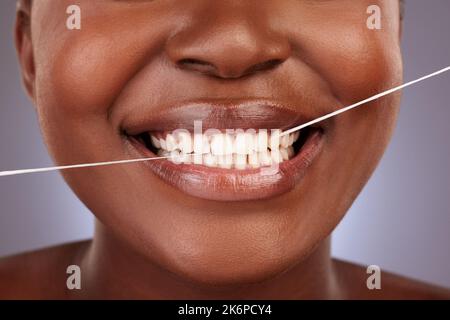 Flossing for healthier teeth. a woman flossing her teeth while wearing ...
