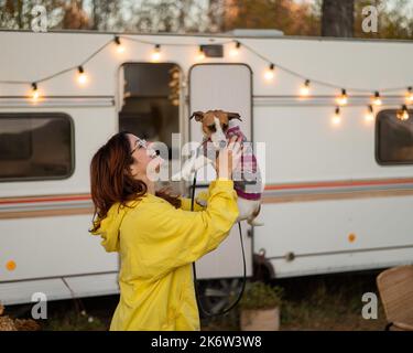 Red-haired Caucasian woman hugs a dog and lives in a motor home. Travel ...