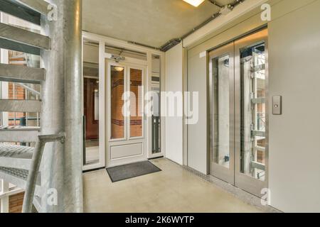 Staircase and elevator located near door and brick wall in hall of ...
