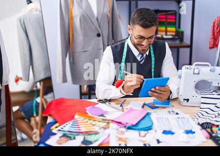 Young hispanic man tailor drawing on touchpad at tailor shop Stock ...