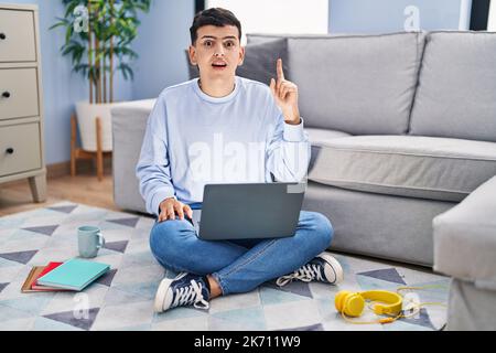 Non binary person studying using computer laptop sitting on the floor ...