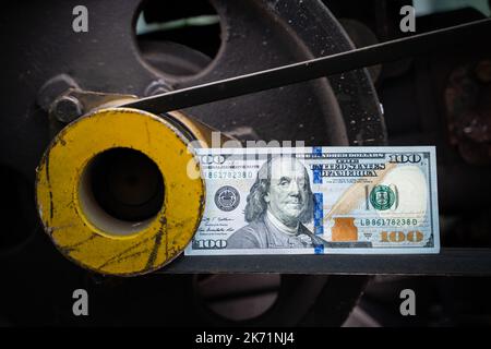 Hundred dollar bill in a tractor pulley close-up with a blurred ...