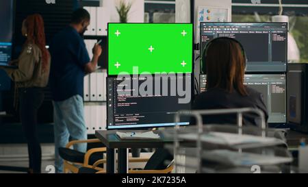 Database developer analyzing greenscreen display on multiple screens, working with server code ...
