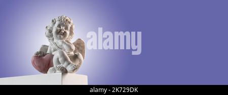 Figurine of an angel Cupid on the podium with a red heart on a very ...