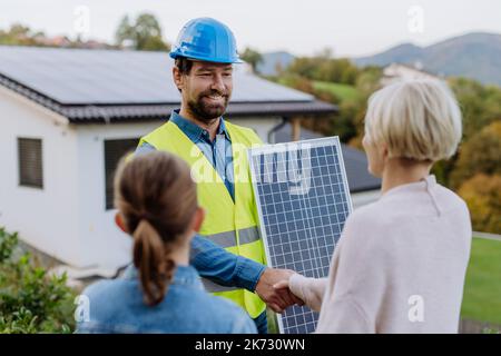 Smiling handyman, photovoltaics panels installer shaking hand with ...
