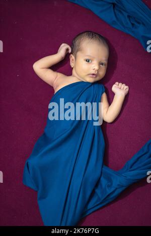 newly born baby laying on red velvet cloth with cute facial expression ...