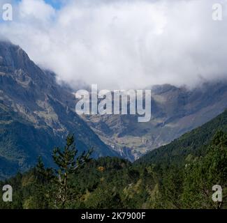 magnificent view of a long glacial forested valley through cloud topped ...