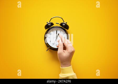 Female hands changing alarm clock for daylight saving time in bedroom ...