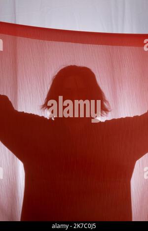 Young man with red transparent fabric in motion against white ...