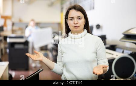 Friendly print shop employee invites customer to come inside Stock ...