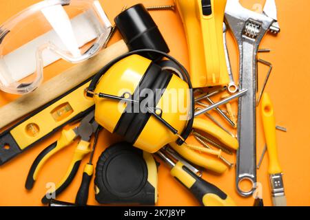 Hearing protectors with builder's tools on table near light wall ...
