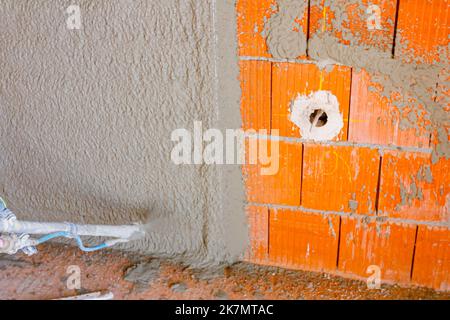 Worker man is holding mortar hose in his hand and plastering under ...