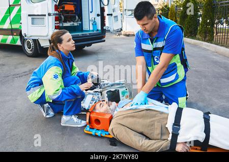 EMS paramedics performing closed-chest cardiac massage and artificial ...