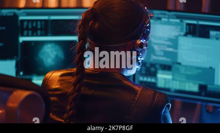 Back view of a Cyberpunk girl types on the keyboard. Multiple computer ...