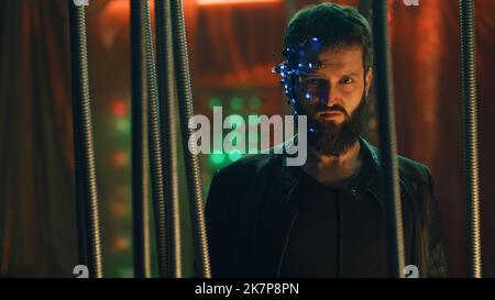 Young brunette guy in Cyberpunk style stands behind the black rods ...