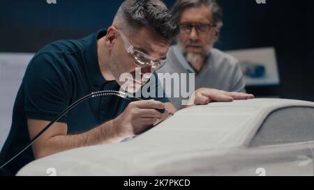 Automotive engineer works on the sculpture of a prototype car model ...