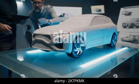 Experienced automotive engineers discuss the car design infront of a ...