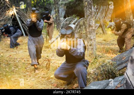 Teams of friends facing on battlefield in outdoor paintball arena ...