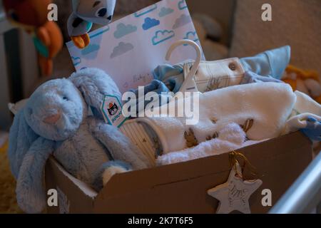 Box with baby clothes, shoes and toy on color background, closeup Stock ...