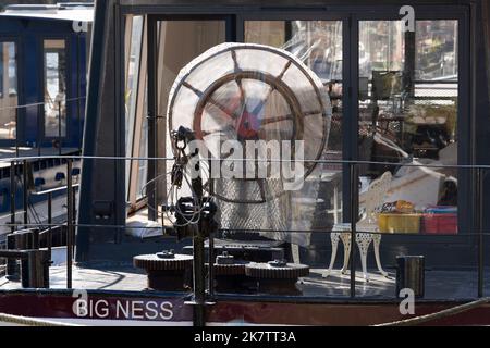 Plastic covers the wheel on the open deck of a houseboat that is moored ...